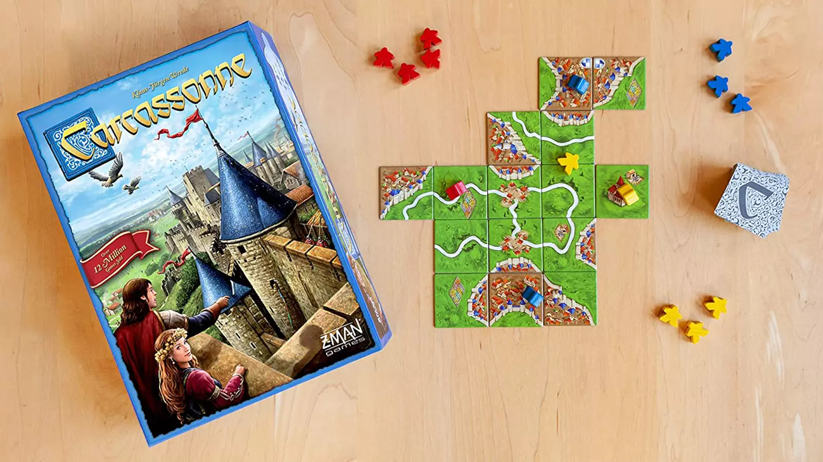 Carcassonne galda spēļu kaste uz koka galda blakus flīzēm un meeples