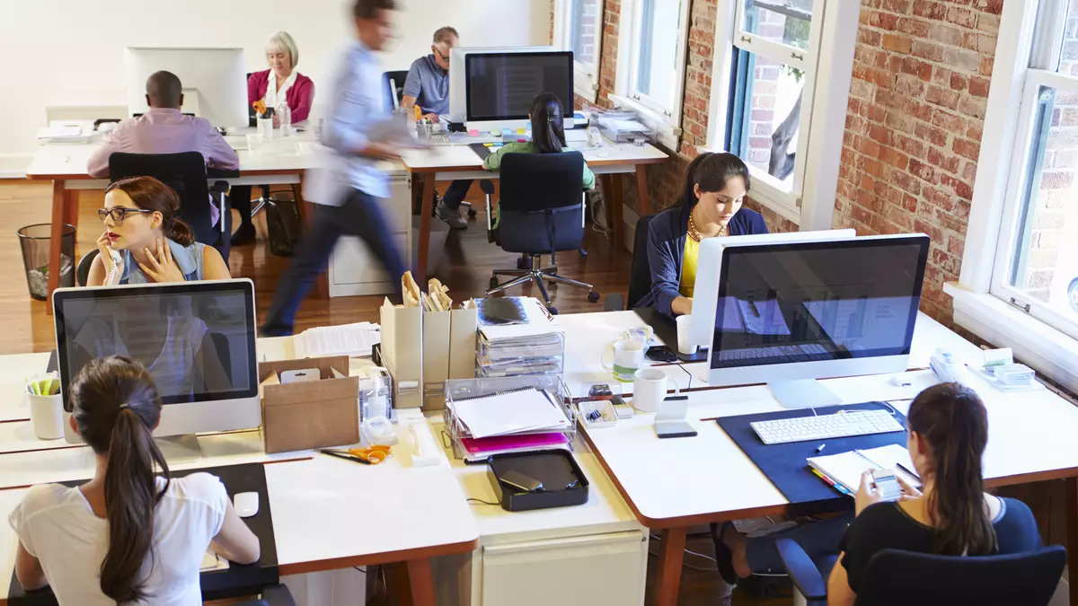 Զբաղված դիզայնի գրասենյակի լայնանկյուն տեսք՝ աշխատասեղանների մոտ աշխատողներով