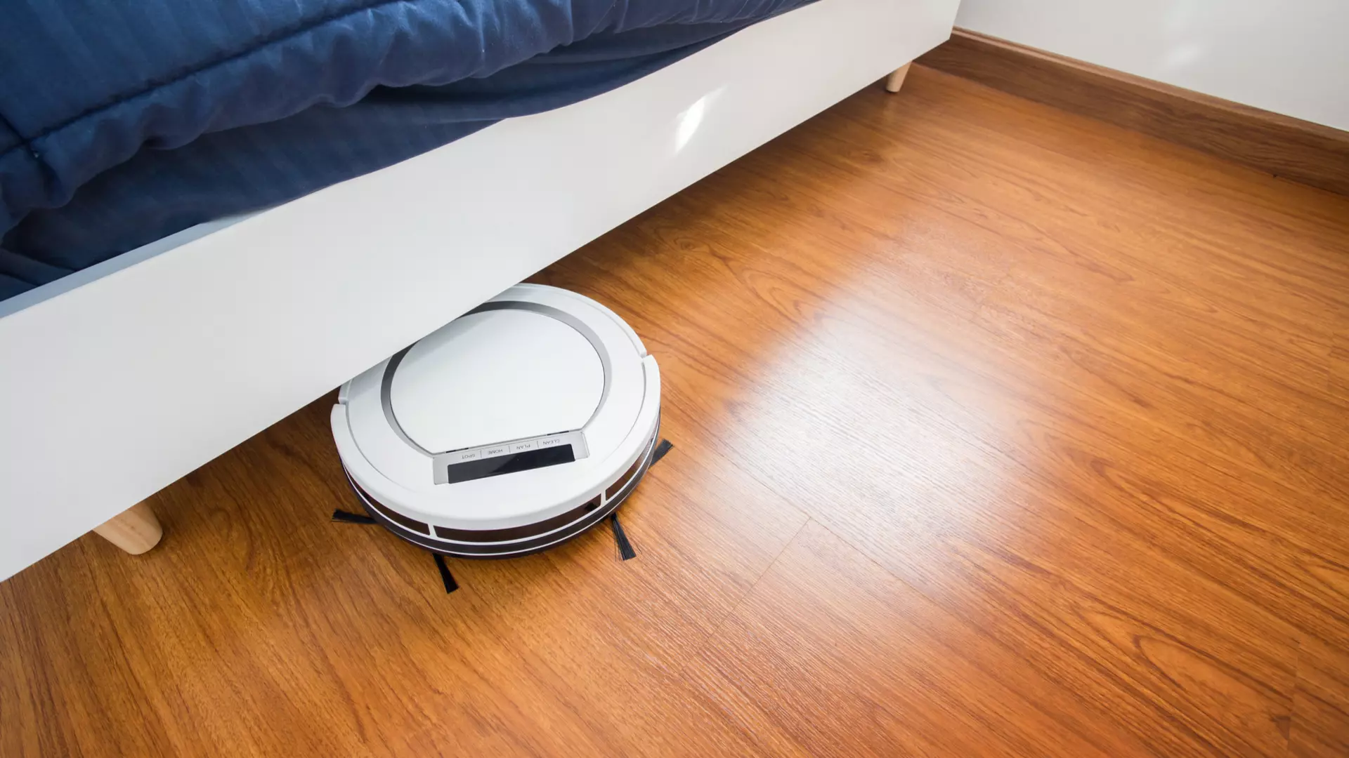 Penyedot debu robot di lantai kayu laminasi di kamar tidur.