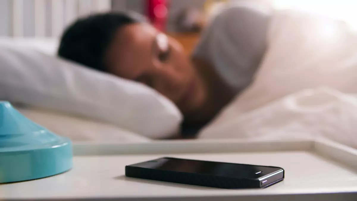 Moteris miega šalia savo telefono.