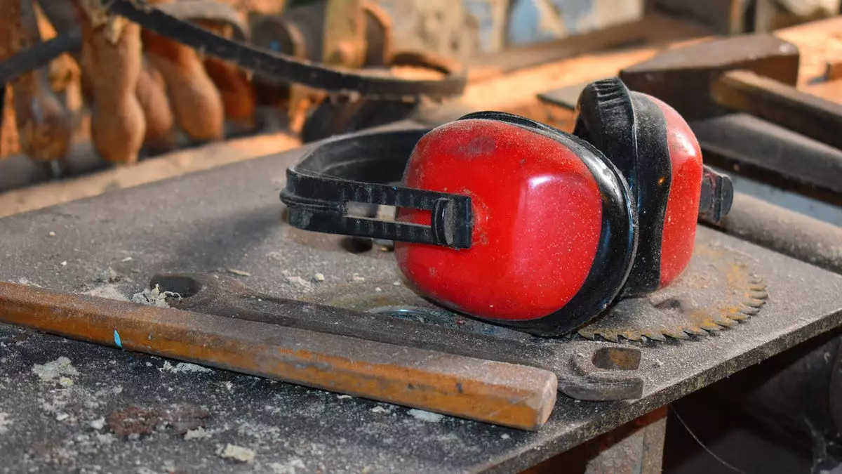 Een rode set geluidsisolerende oorkappen op een werkbank.
