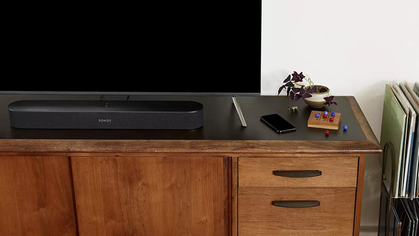 Barra de sonido Sonos Beam en un soporte de entretenimiento con un televisor y otra decoración