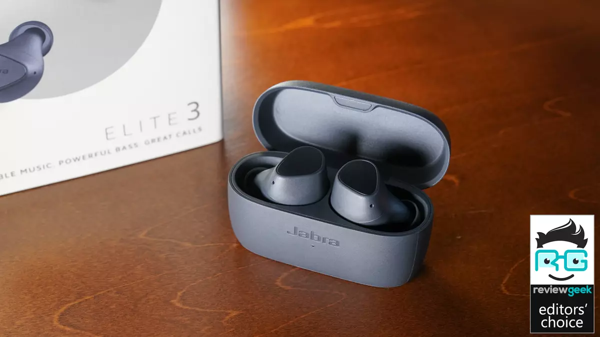 Τα ακουστικά Jabra Elite 3 στη θήκη τους με το καπάκι ανοιχτό σε ένα τραπέζι δίπλα στο κουτί που συνοδεύουν