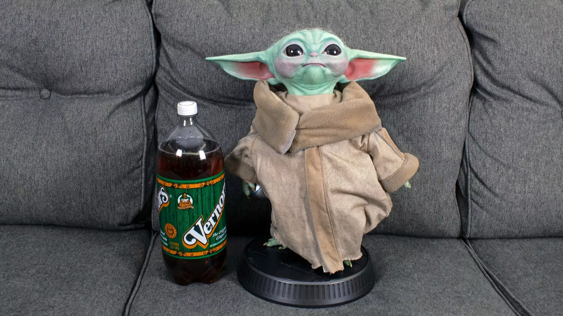Baby Yoda staat groter dan een fles frisdrank van 2 liter.