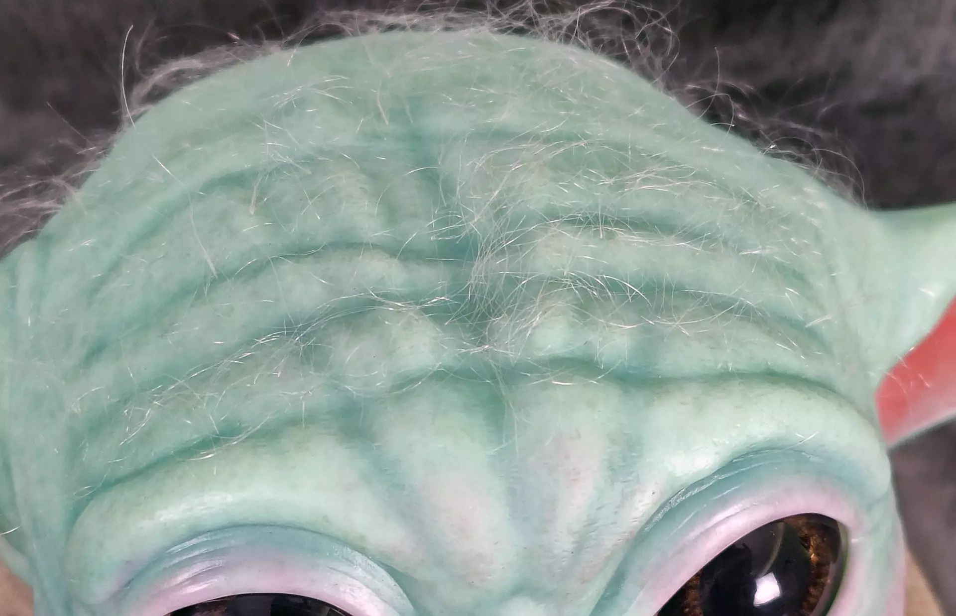 En närbild av Baby Yodas whispy hårstrån.