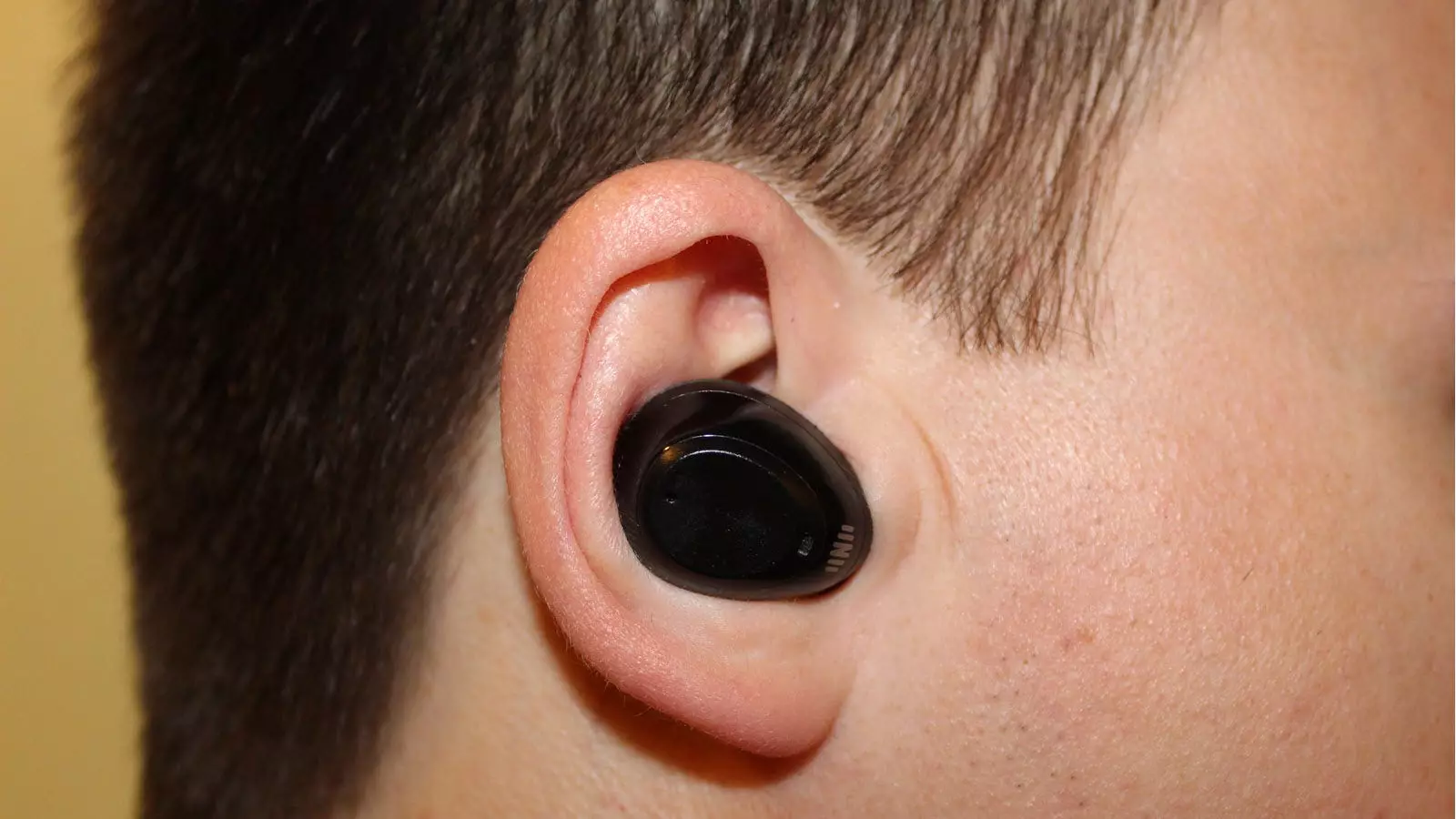 Nuheara IQBuds Boost が耳に挿入され、相対的なサイズが表示されます。