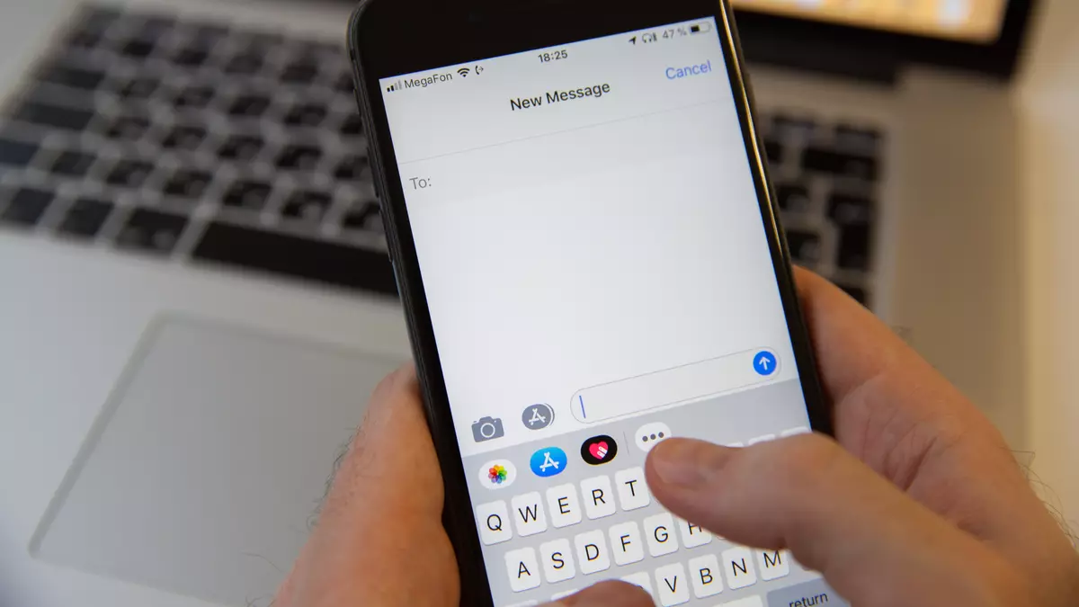 मैकबुक के साथ पृष्ठभूमि पर आईफोन पर एक नया संदेश टाइप करना