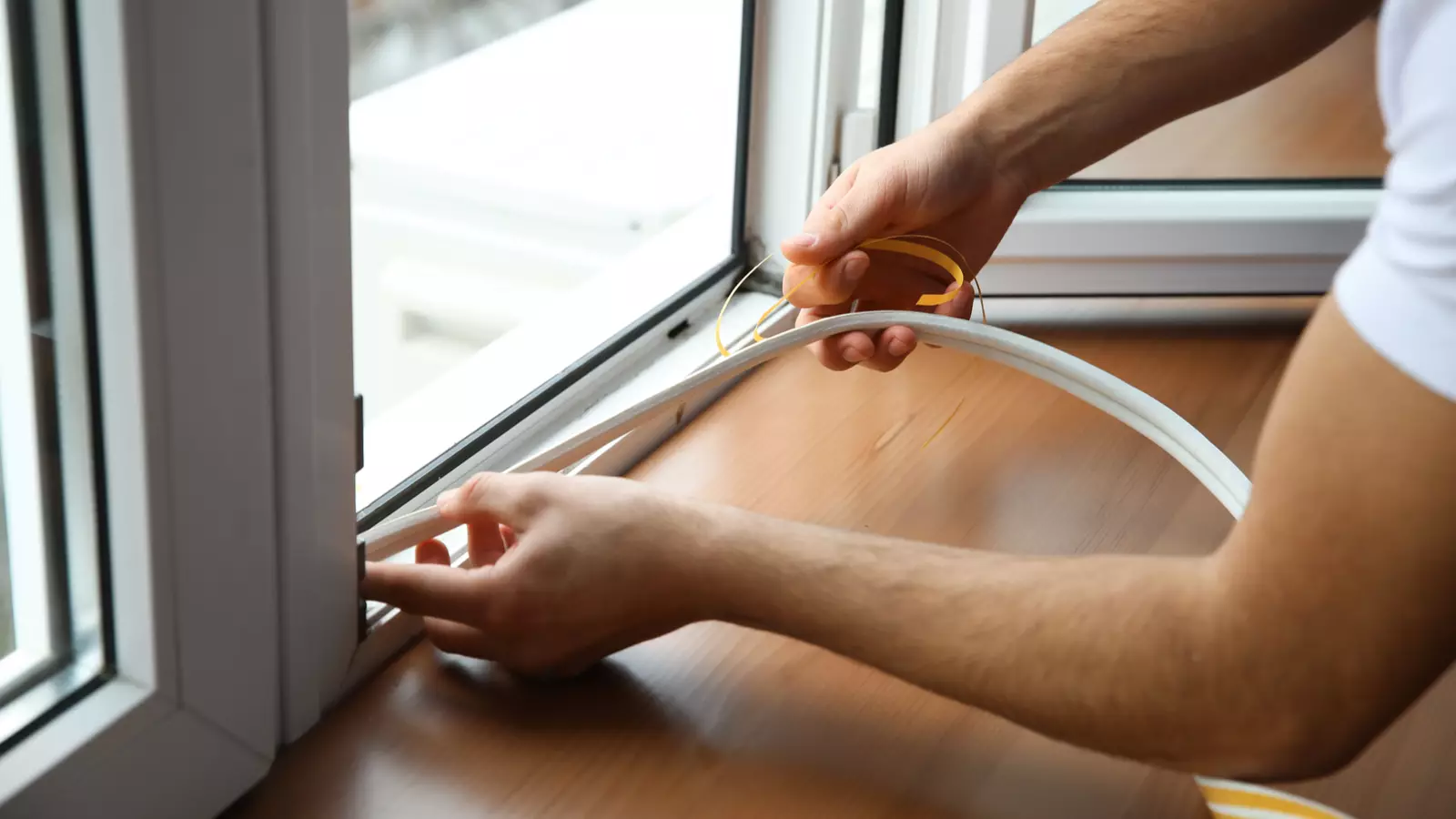 ung arbetare som installerar fönstertätning i ett hus