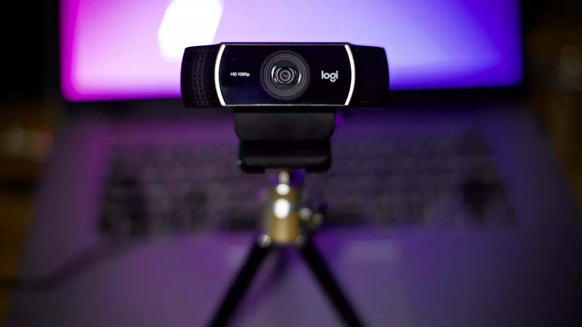 eine Logitech-Webcam auf einem kleinen Desktop-Stativ vor einem bunten Bildschirm
