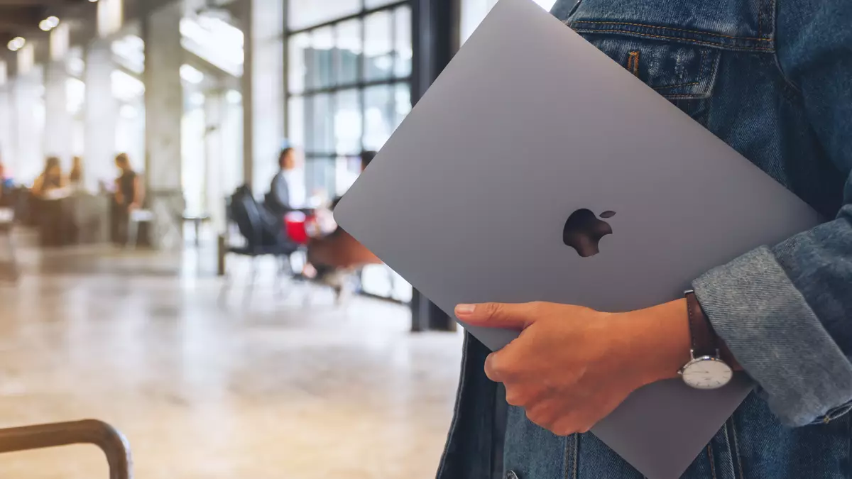 MacBook en la mano de un usuario mientras camina