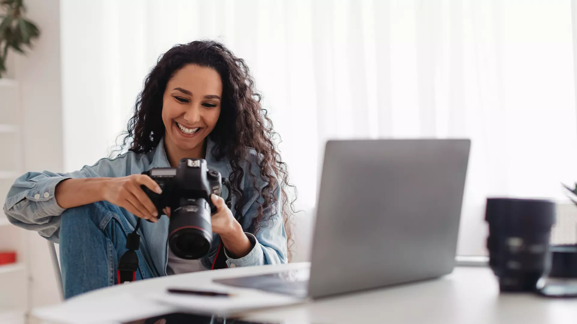 Fotograf koji se igra sa svojom kamerom ispred laptopa.