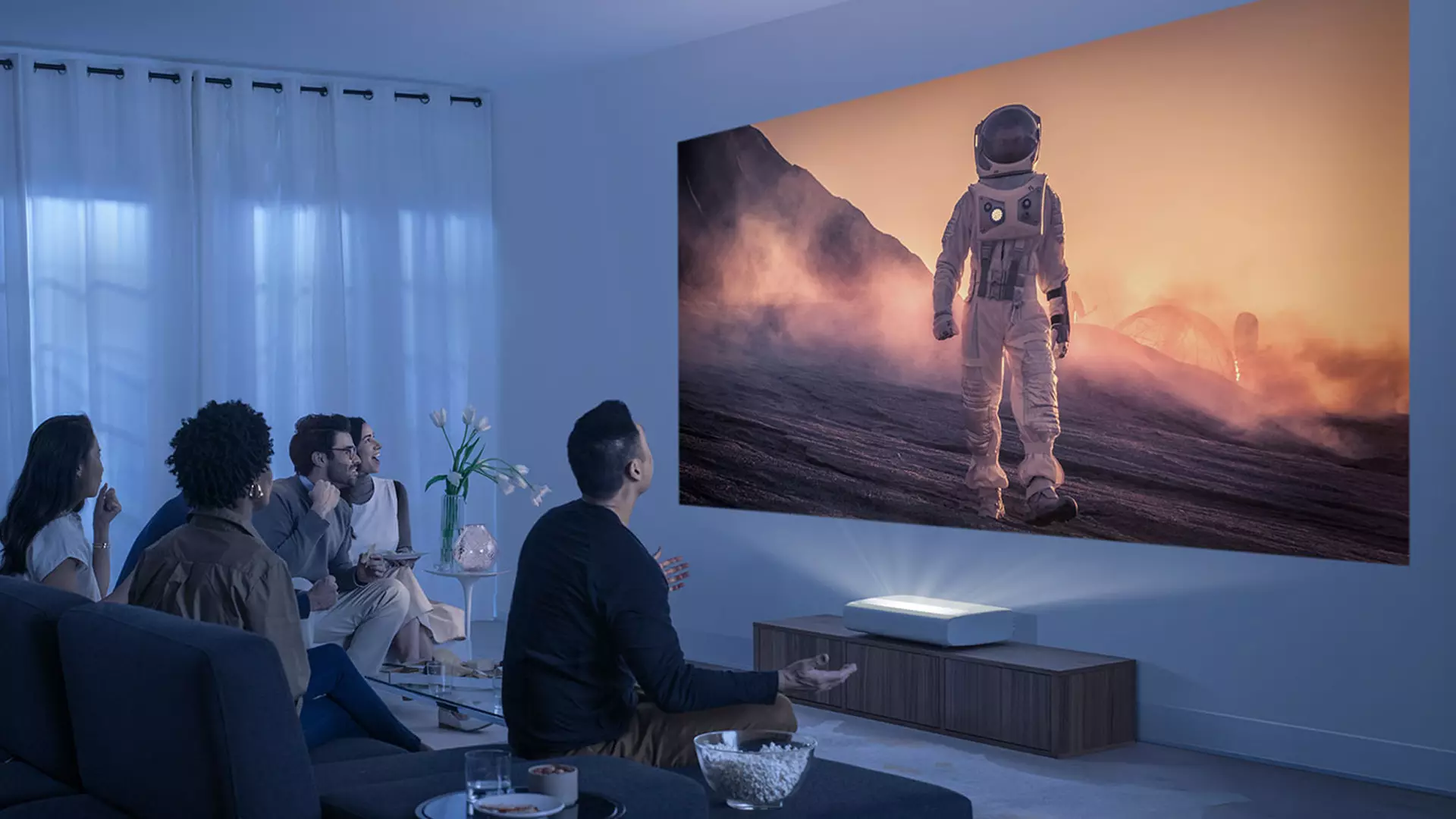 Samsung Premiere 超短焦点プロジェクターで映画を見ている人々。