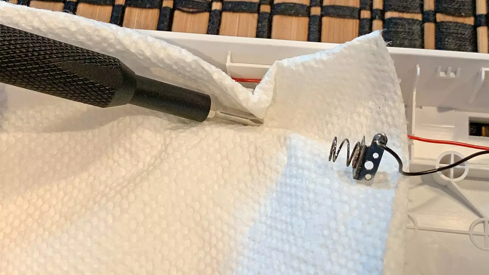 ब्याट्रीको डिब्बामा पेपर तौलिया थिचेर स्क्रू ड्राइभर।