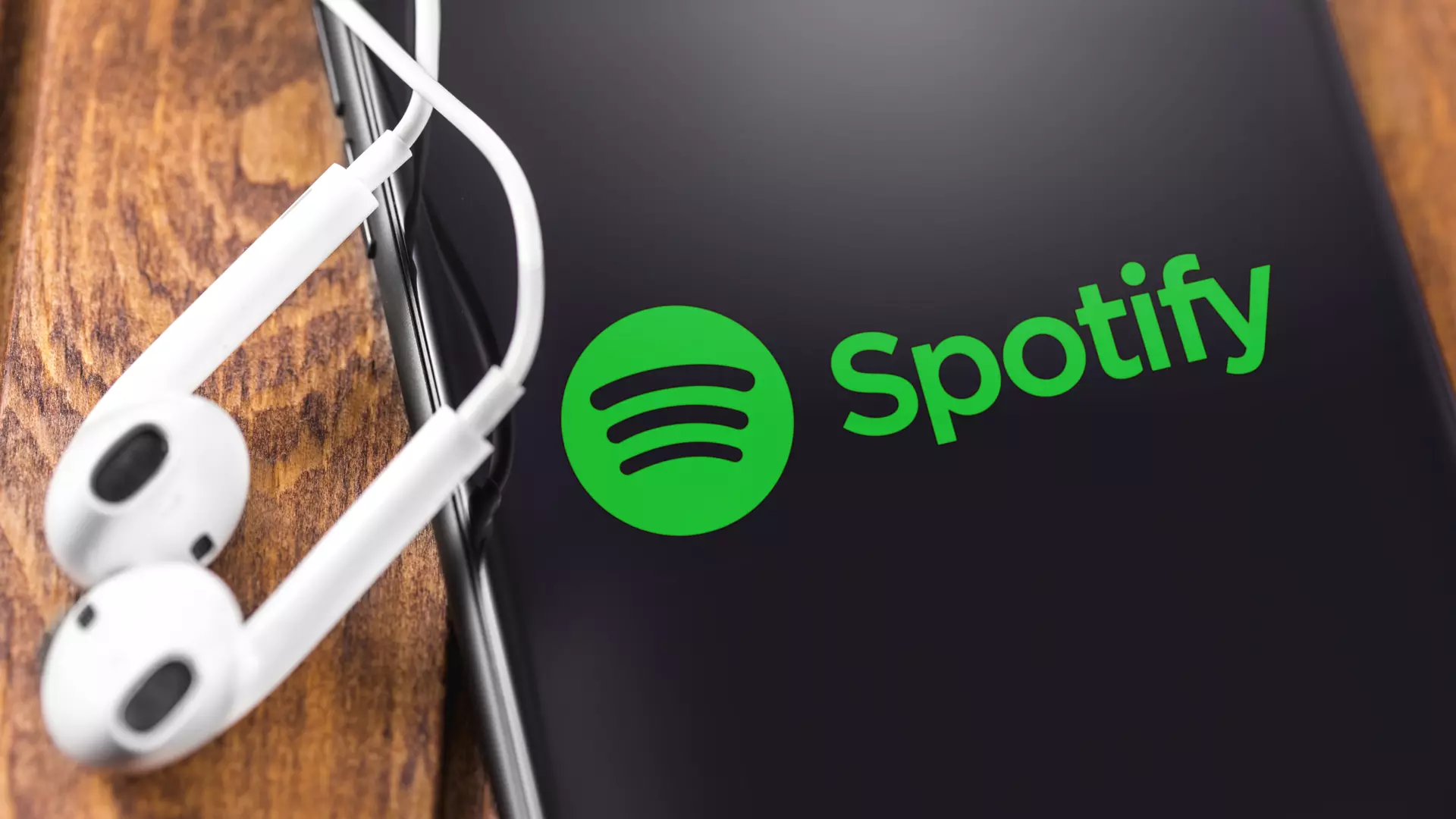 Ekranda Spotify logosu olan Apple Earpods ve iPhone. Spotify - çevrimiçi akışlı ses hizmeti.