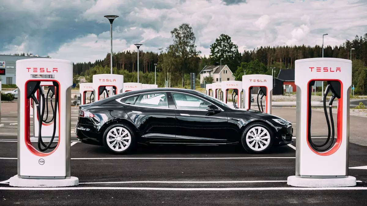 Parcio Tesla Model S wrth ymyl llinell o Superchargers
