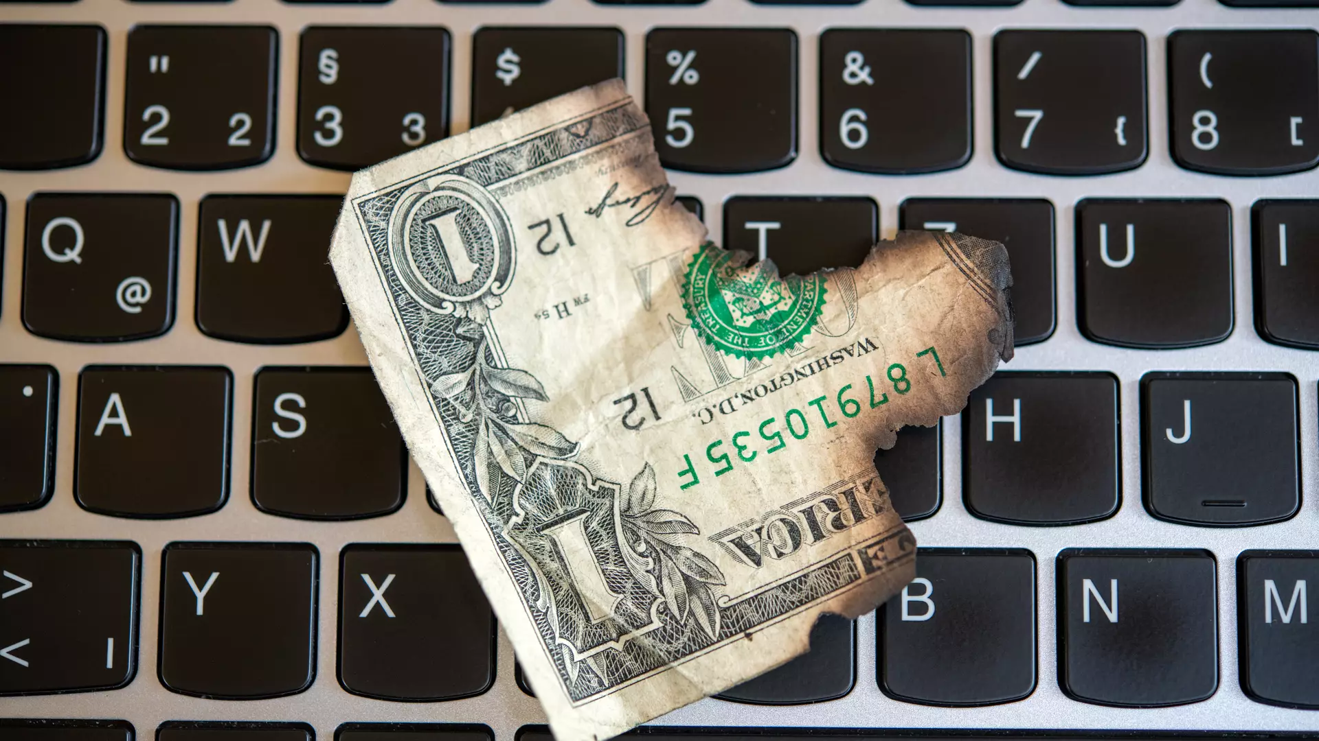 Un portátil cun billete de dólar queimado no teclado