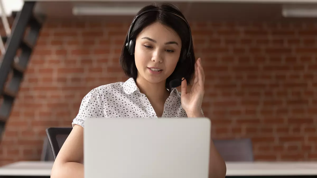 En kvinna tittar på en video medan hon bär trådlösa hörlurar.