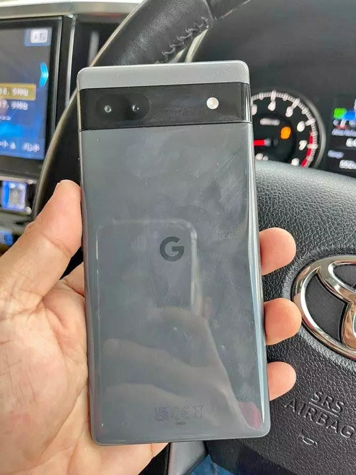 Google Pixel 6a a la mà d'algú, la part posterior cap amunt.