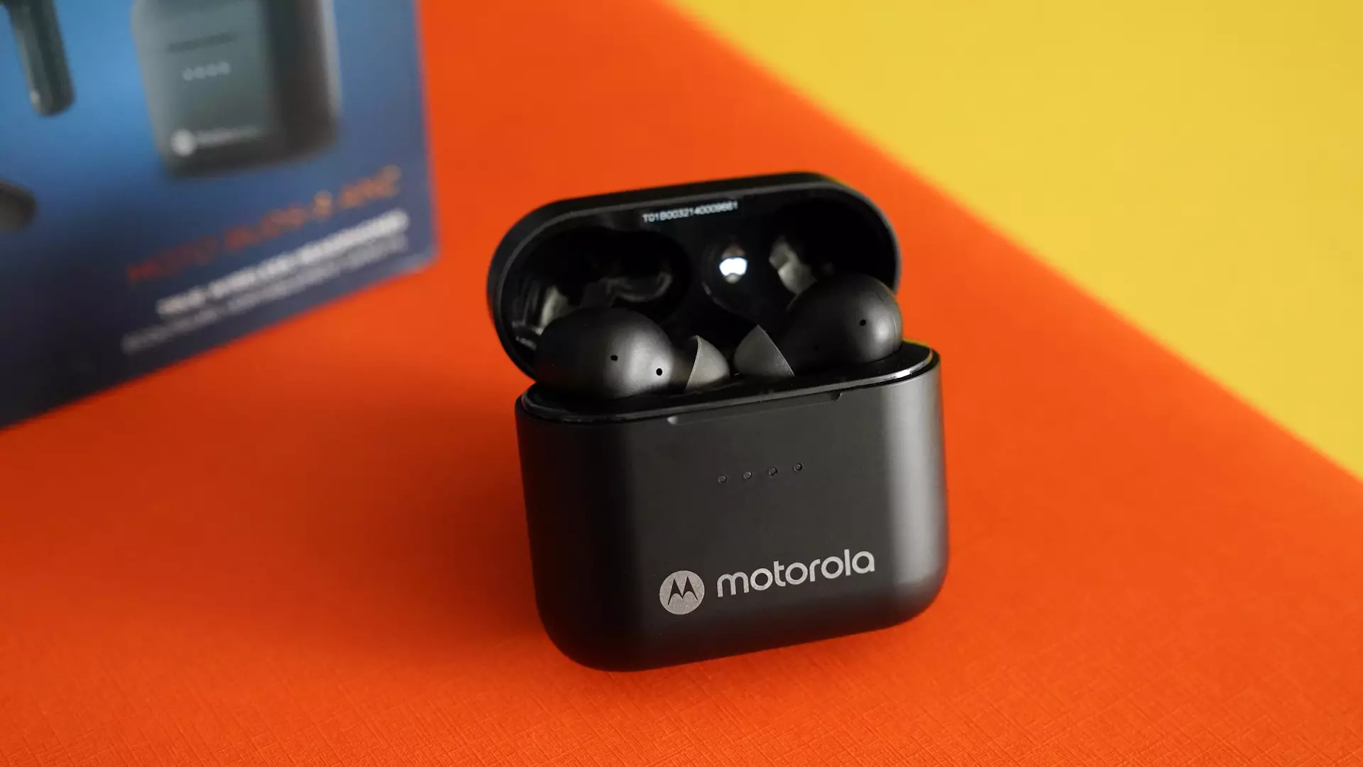 Навушники Moto Buds у зарядному футлярі з відкритою кришкою та упаковкою за ними.