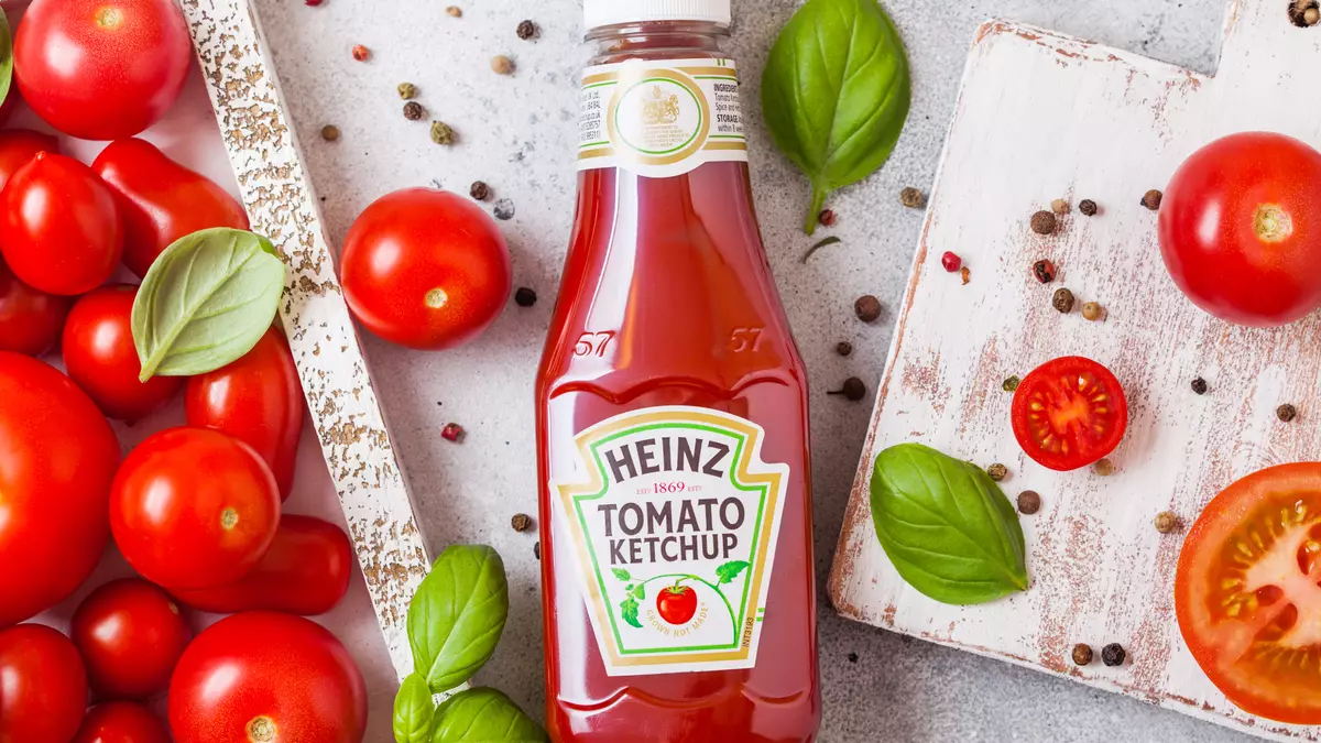 Ketchup Heinz con tomates crus frescos en caixa sobre fondo de pedra.