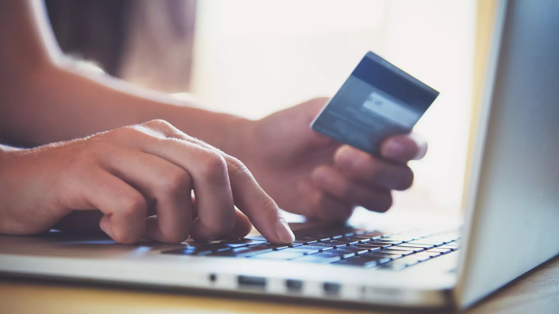 ידיים אוחזות בכרטיס אשראי ומשתמשות במחשב נייד. קניות באינטרנט