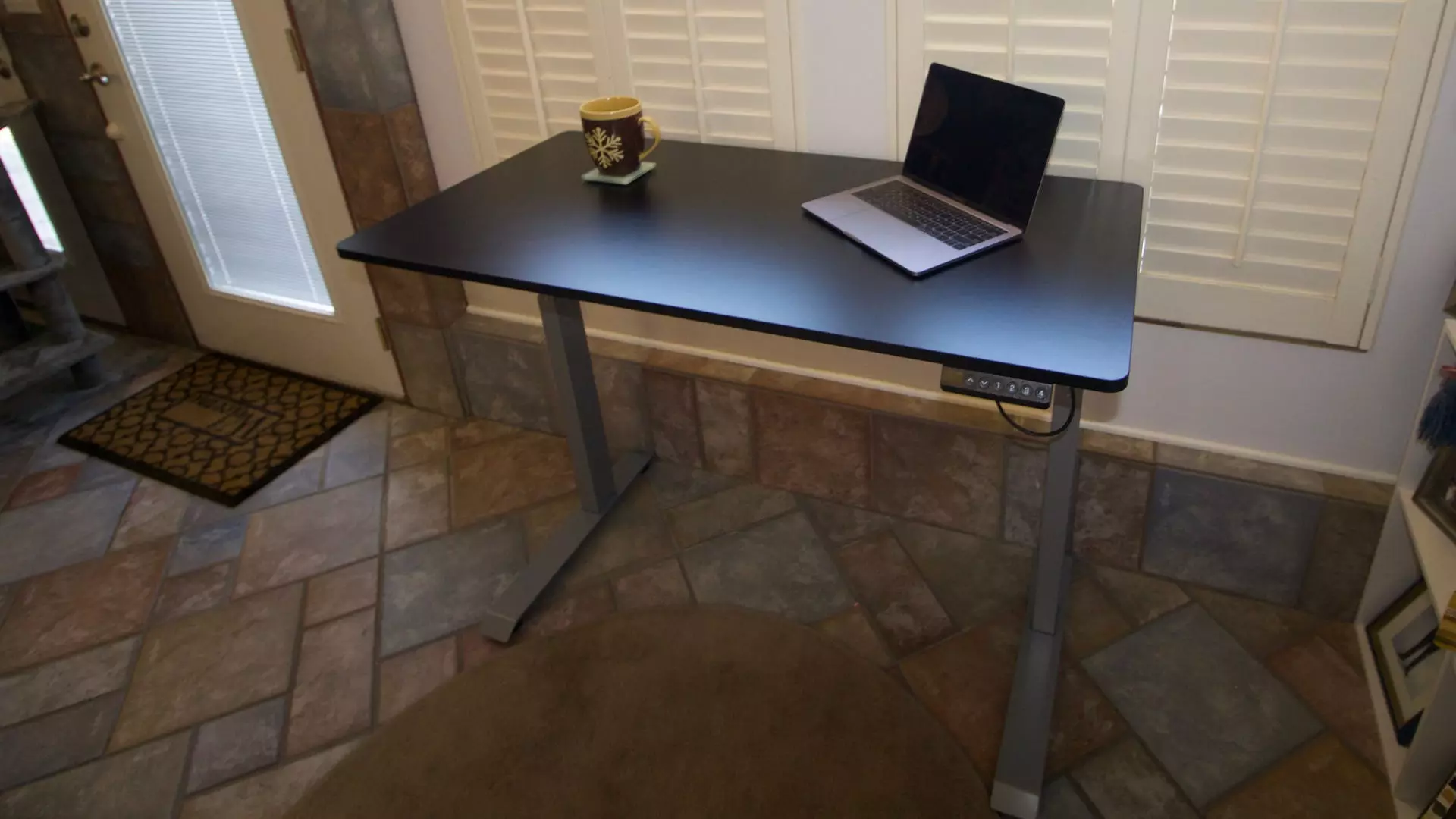 Pisalna miza Victor High Rise s prenosnim računalnikom in skodelico za kavo na površini.
