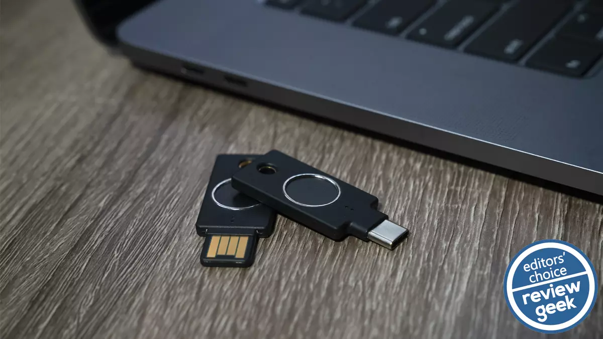 Και οι δύο εκδόσεις USB-C και USB-A των κλειδιών ασφαλείας της σειράς YubiKey Bio σε ένα tablet δίπλα σε φορητό υπολογιστή