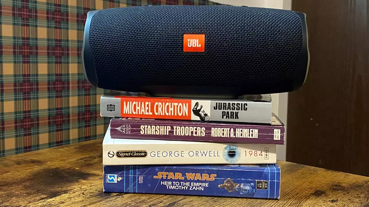 Speaker Bluetooth berada di atas tumpukan buku fiksi ilmiah paperback.