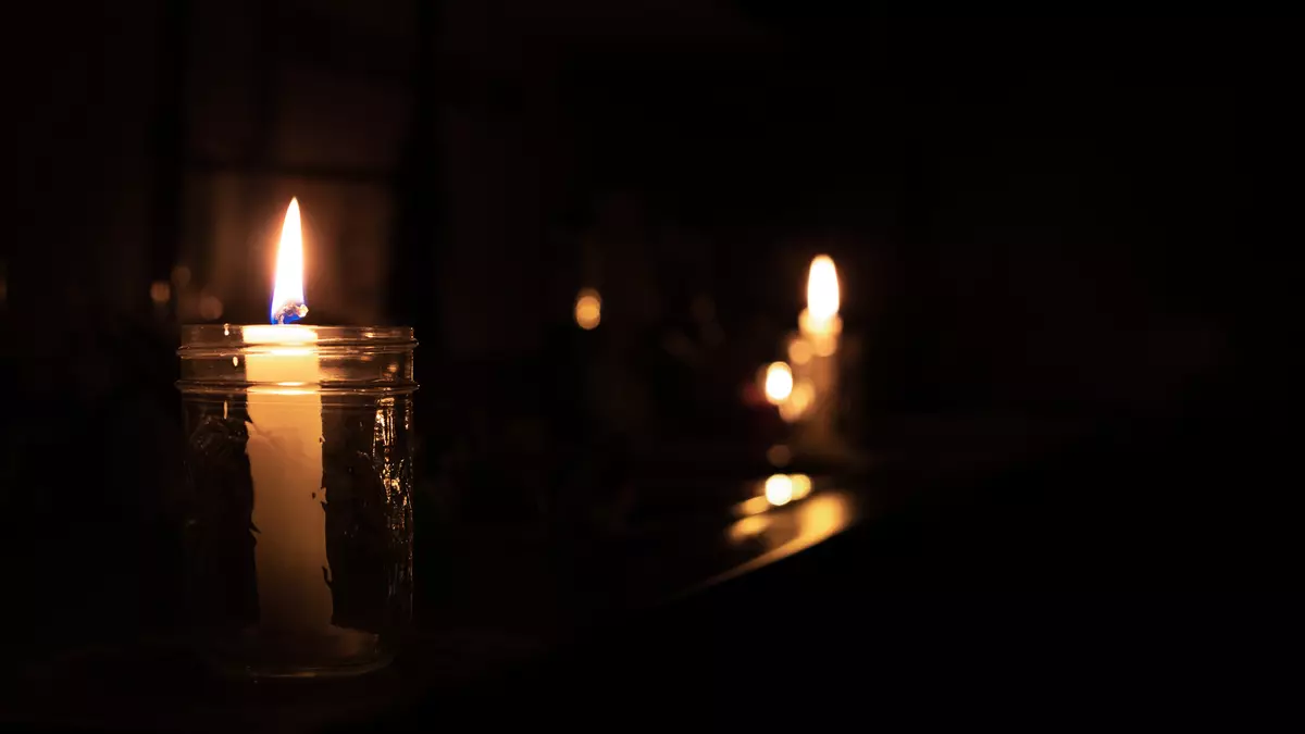 Unha vela acesa nunha habitación sen enerxía.