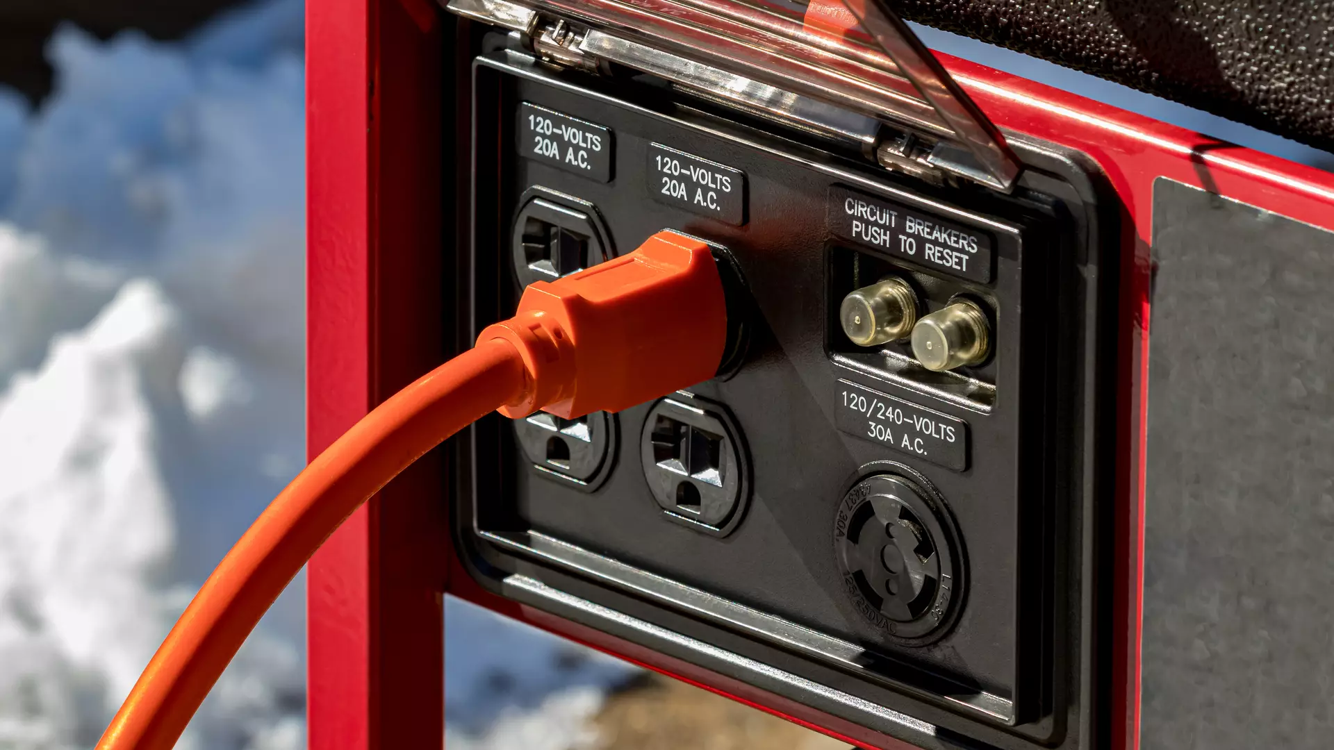 Червен резервен генератор с включени в него кабели.