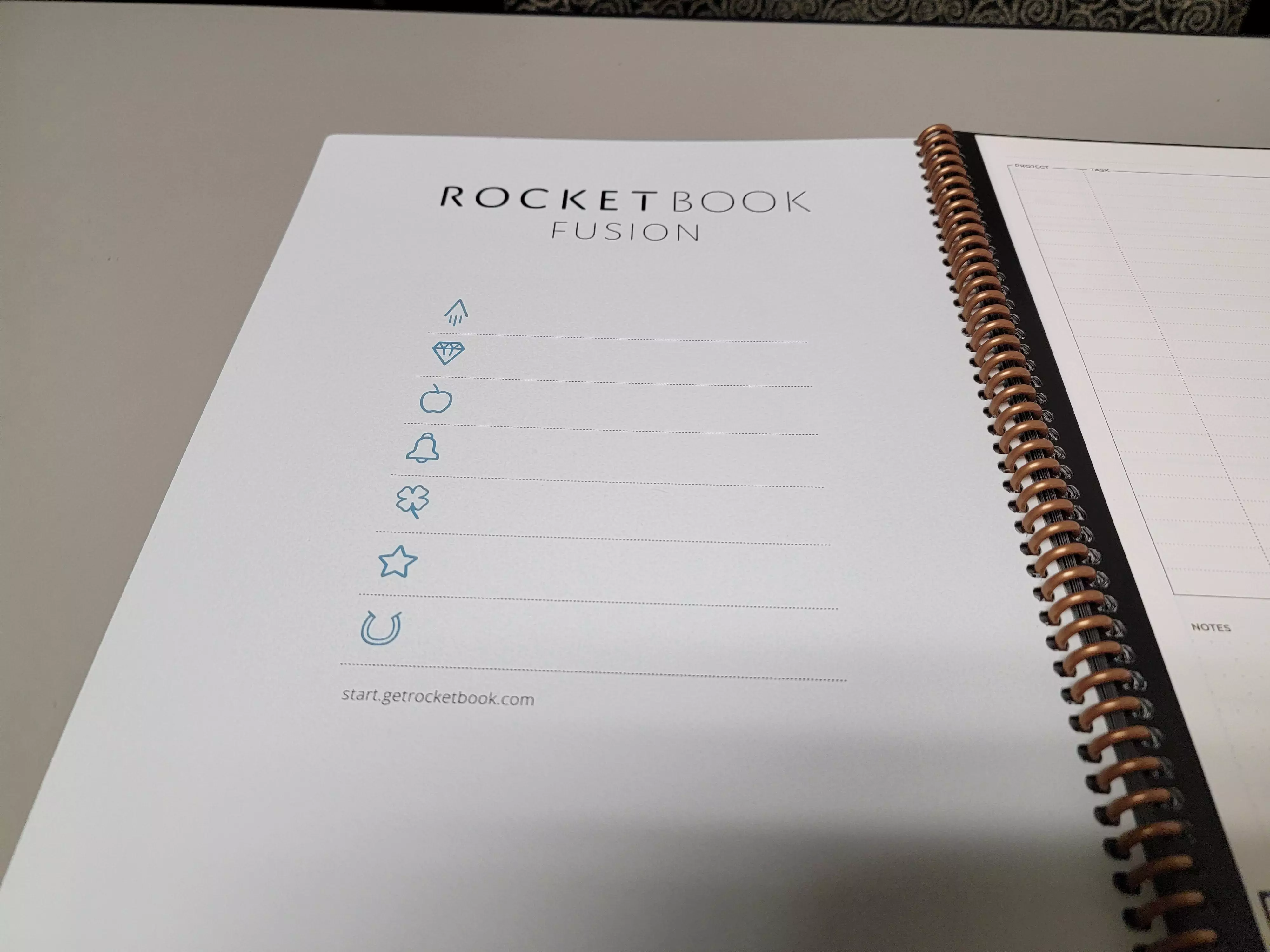 Rocketbook Fusion блокнотунун ички мукабасы, сканерлөө багыттарын билдирген ар кандай символдорду көрсөтөт.