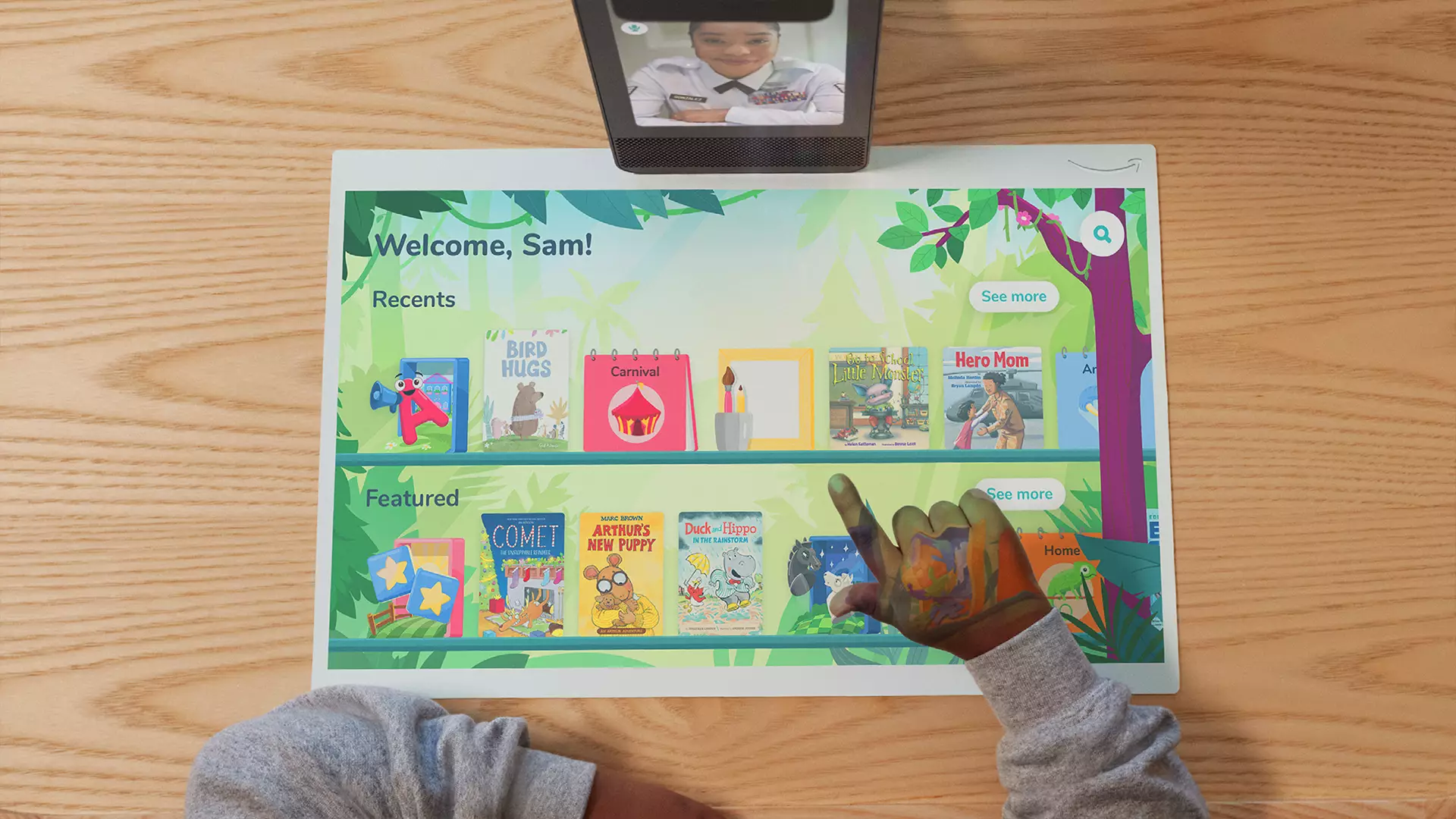Vaikas naudojant Amazon Glow su knygomis, projektuotomis ant stalo.