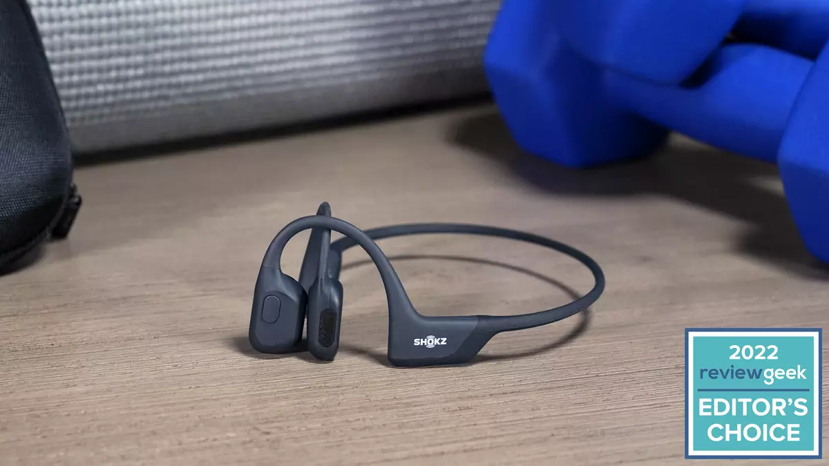 Ang Shokz OpenRun Pro bone conduction headphones mula sa kaliwang bahagi, nakaupo sa isang mesa sa tabi ng yoga mat at dumbbells.