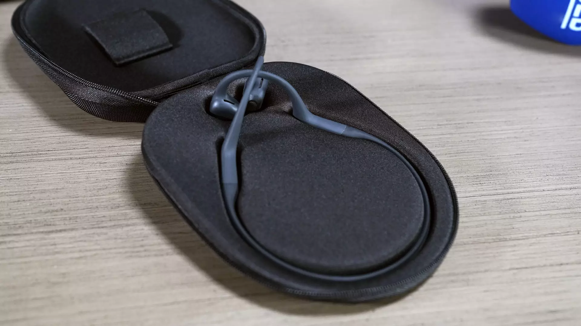 Shokz OpenRun Pro slušalice za koštanu provodljivost u svojoj torbici s otvorenim poklopcem sjede na stolu.