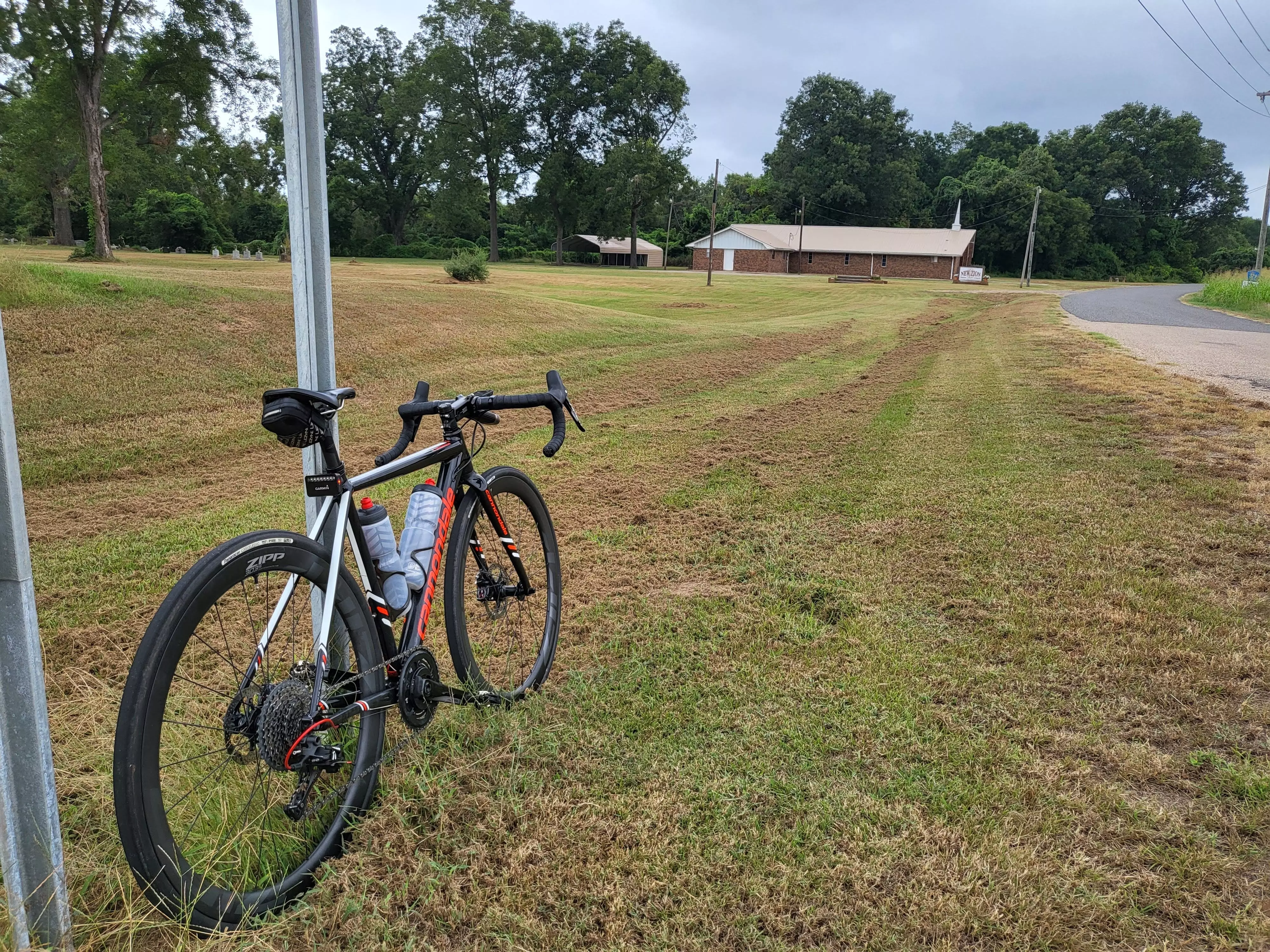 Una bicicleta, hierba verde, iglesia al fondo.