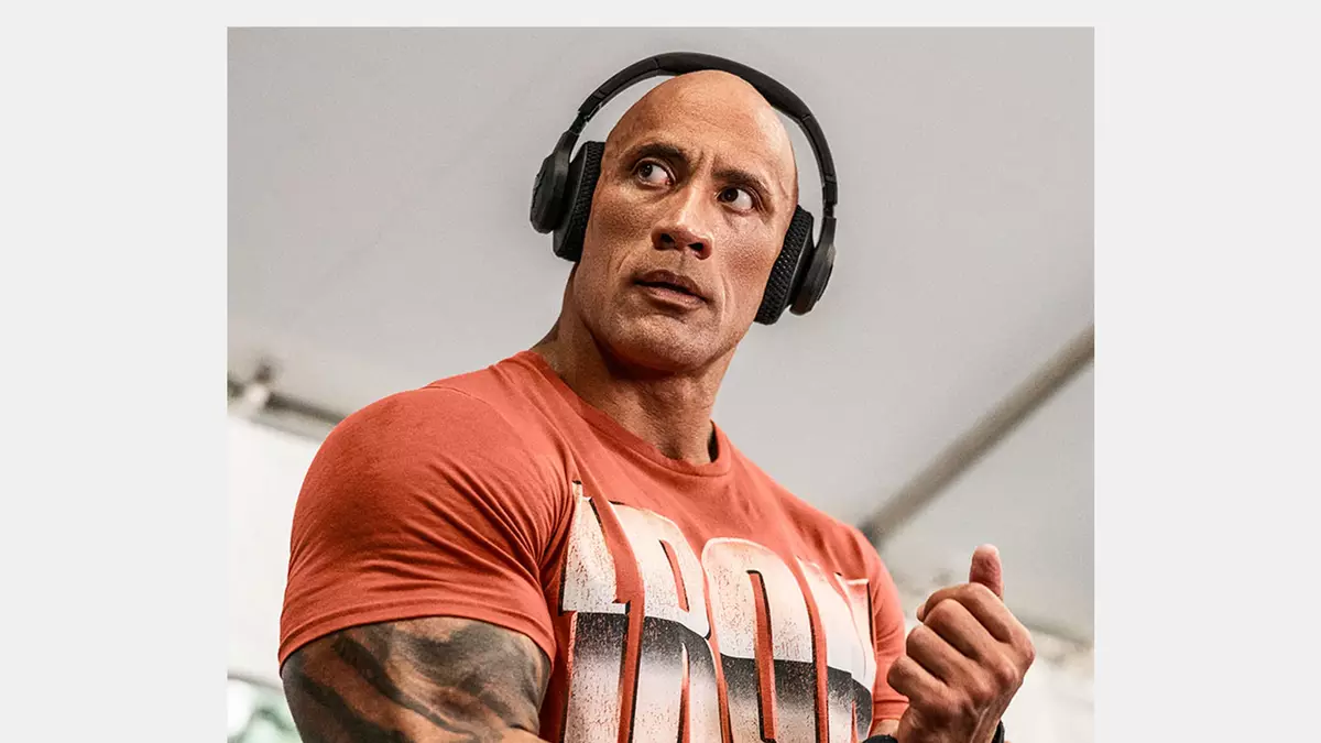 The Rock သည် သူ၏ UA Project Rock Over-Ear Training Headphones.f ကို ၀တ်ဆင်ထားသည်။