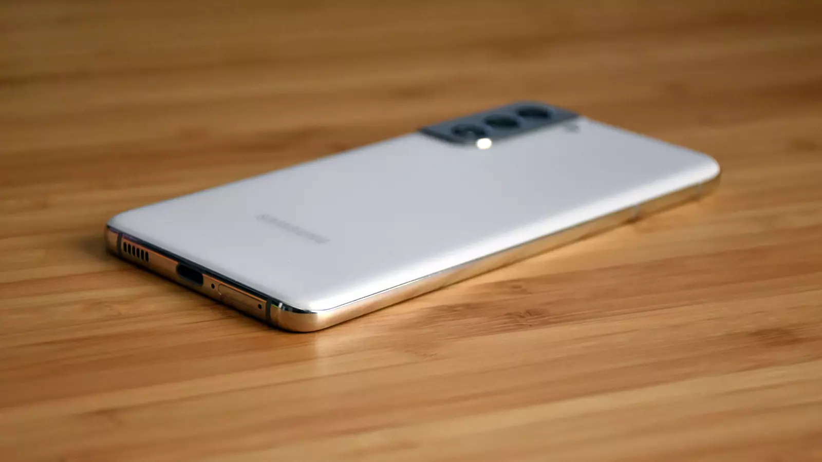 Samsung Galaxy S21-ის უკანა და ქვედა კუთხიანი ხედი ხის მაგიდაზე