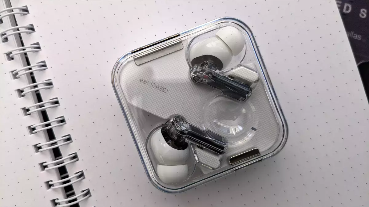 Фотографија од слушалките Nothing Ear 1 на бело парче хартија. Хартијата се прикажува низ проѕирното куќиште на увото 1.