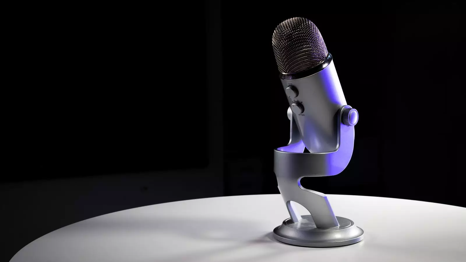 Blauwe Yeti-microfoon op een zilveren tafel tegen een zwarte achtergrond