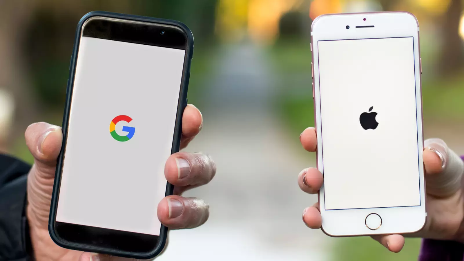Tangan memegang telefon Android dan iPhone bersama-sama memaparkan logo masing-masing