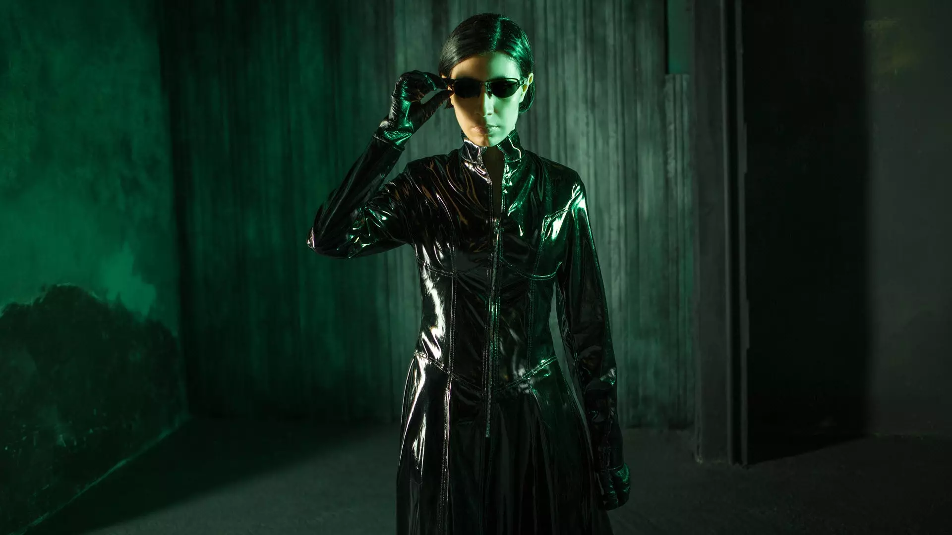 一个穿着绿色的年轻女子，穿着像“黑客帝国”中的角色 Trinity。