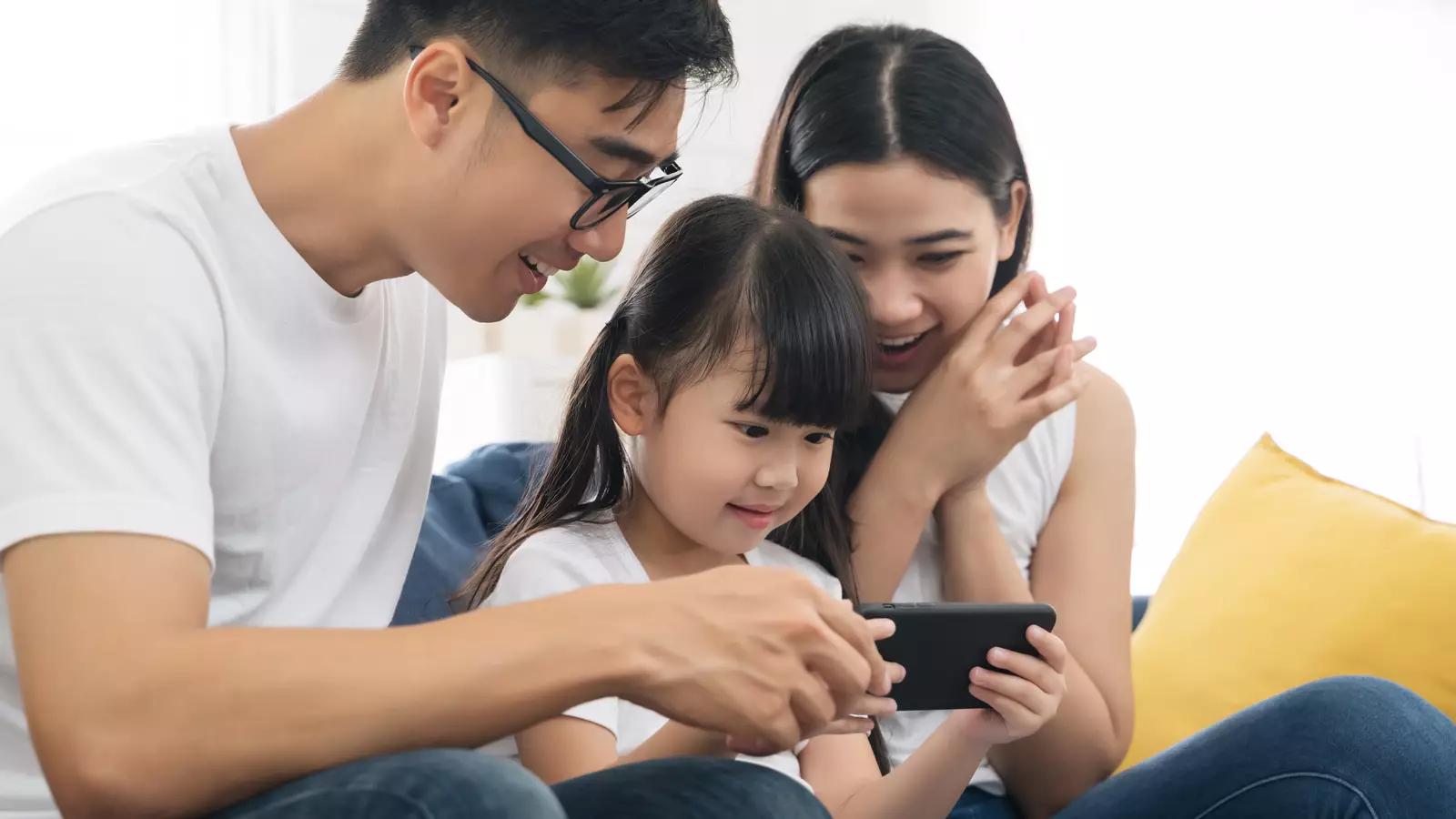 Азиско семејство користи паметен телефон со мала ќерка дома