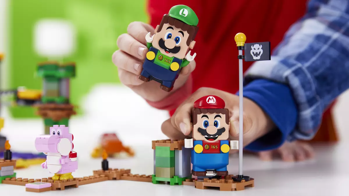 Două mâini de copii ținând Bluetooth LEGO Mario și LEGO Luigi