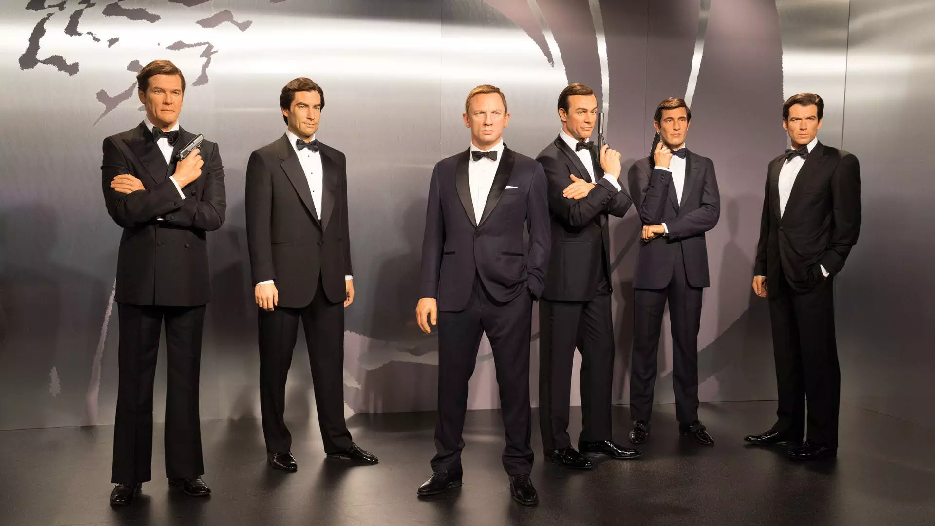 Sve različite verzije Jamesa Bonda koji stoji ispred filmske pozadine.