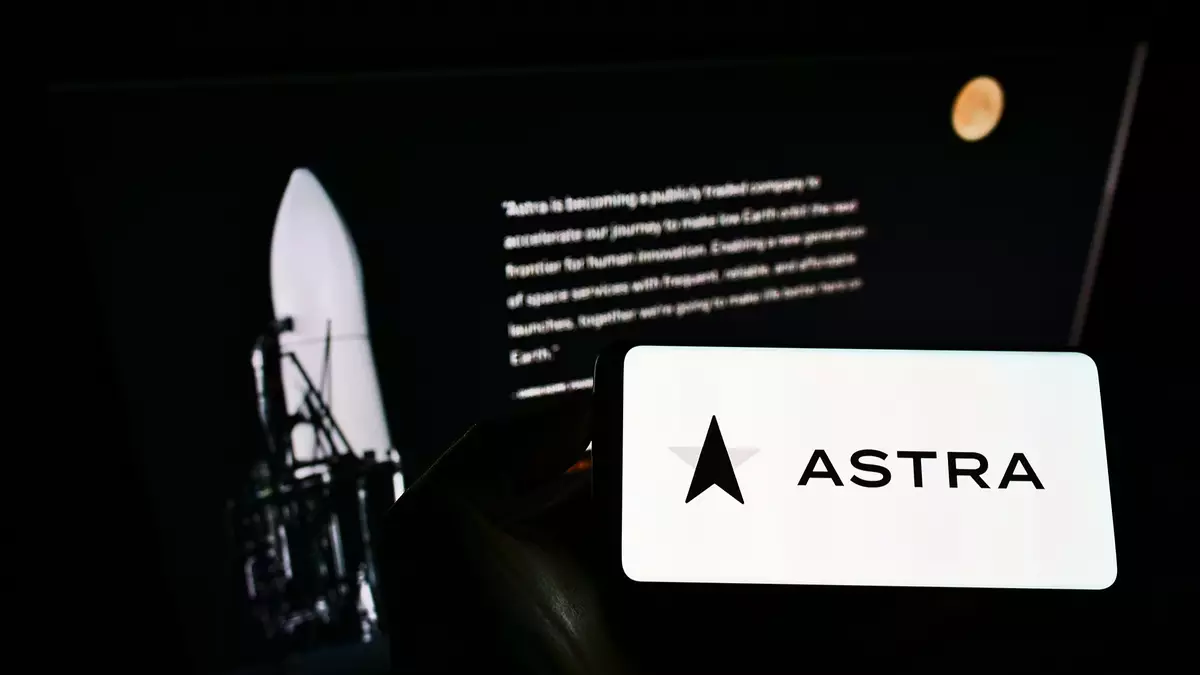 Persono tenanta poŝtelefonon kun emblemo de usona aerospaca kompanio Astra Space Inc. sur ekrano antaŭ retpaĝo