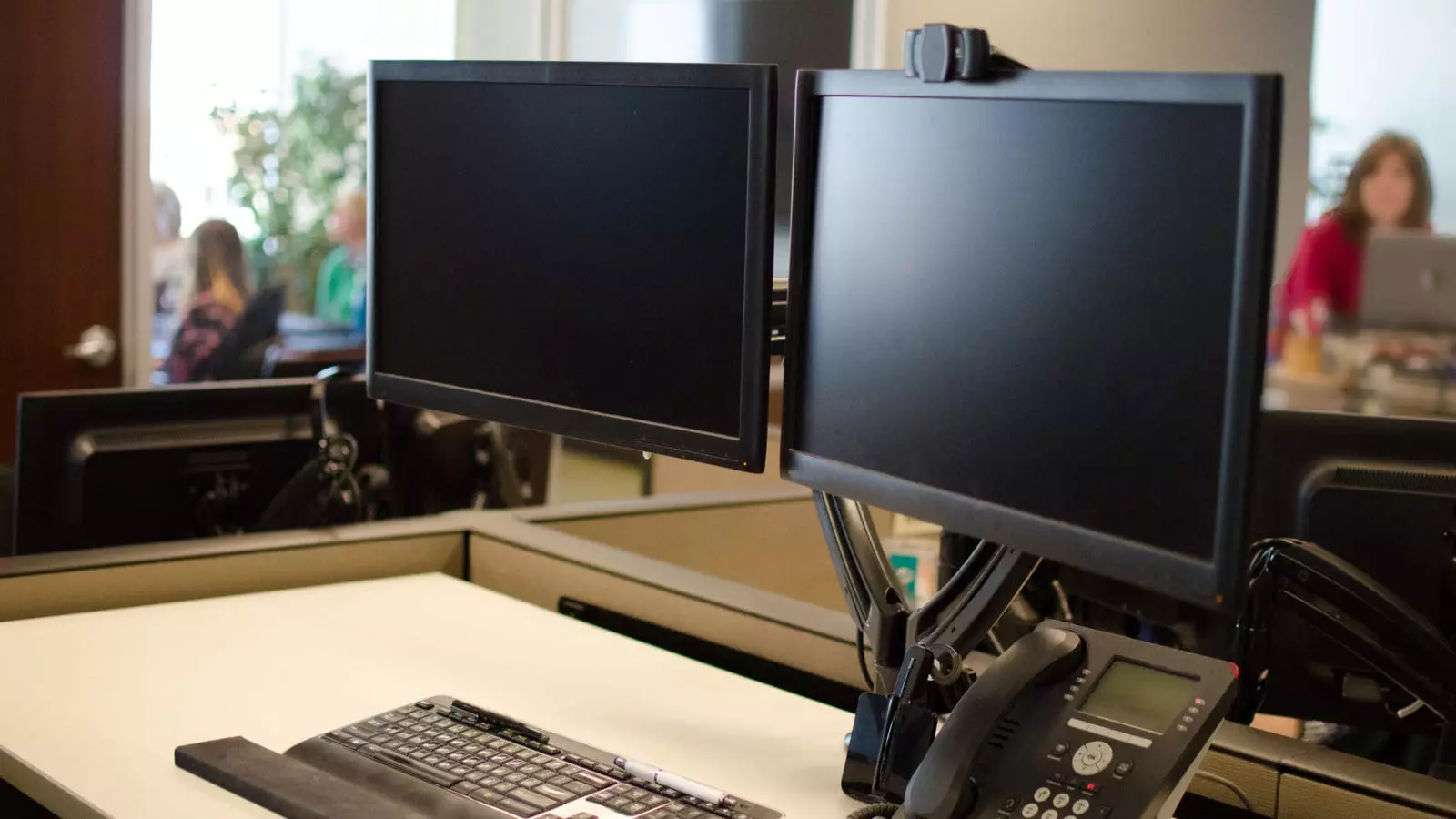 Dy monitorë në një stendë në një zyrë