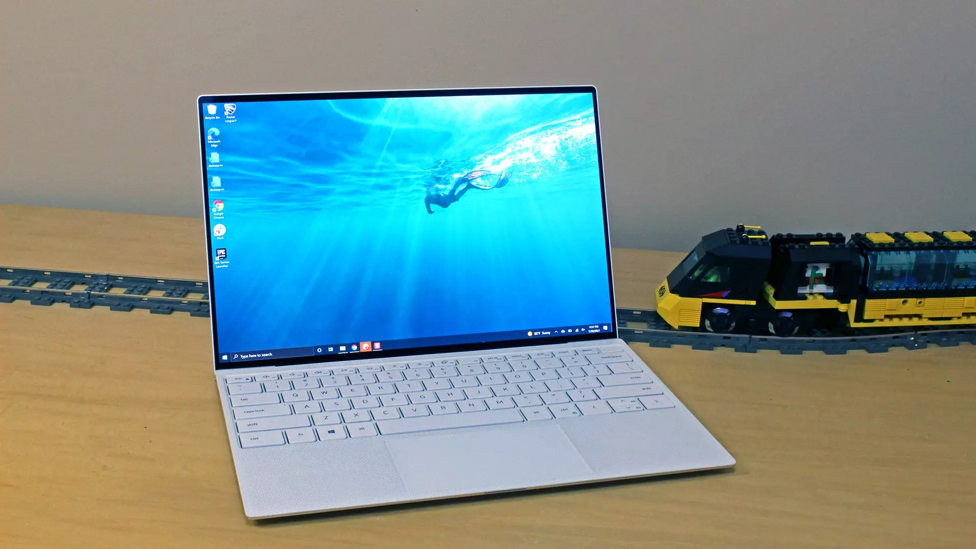 De XPS 13 OLED-laptop zit op een tafel met een speelgoedtrein op een treinspoor erachter.