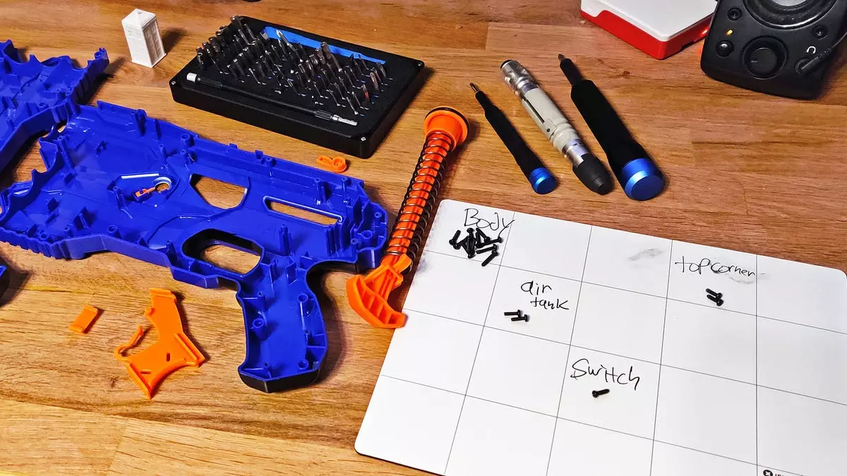 Bi iFixit kit urratutako Nerf pistola batez inguratuta.