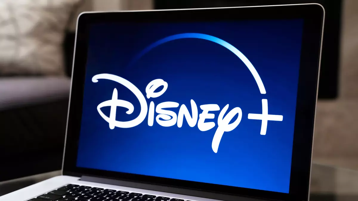 Disney + logo iepen op Apple laptop op tafel neist kom popcorn