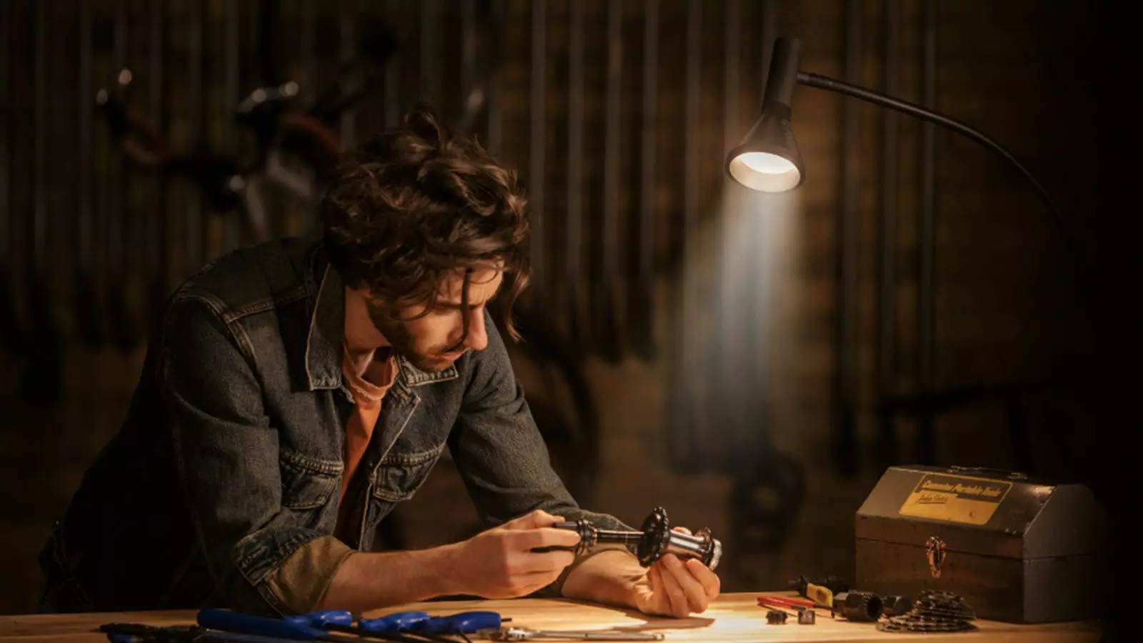En mand, der arbejder på en værktøjsbænk under en gulvlampe.
